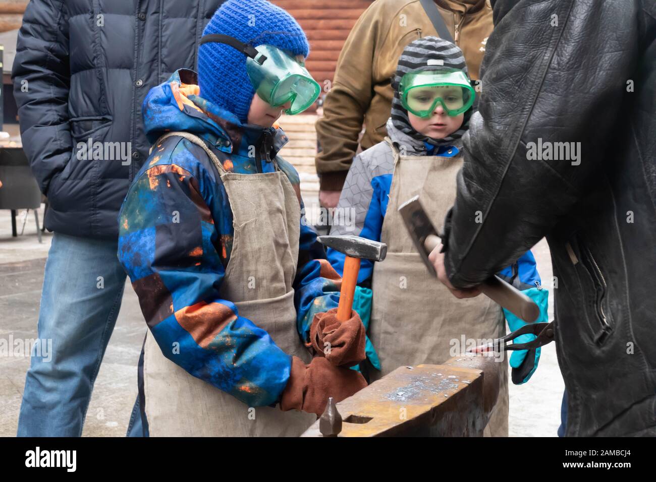 Kids learning blacksmithing with a hammer and glasses Stock Photo - Alamy