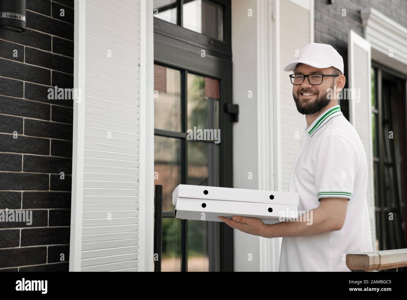 Side view of happy joyful young male courier in white polo and cap ...