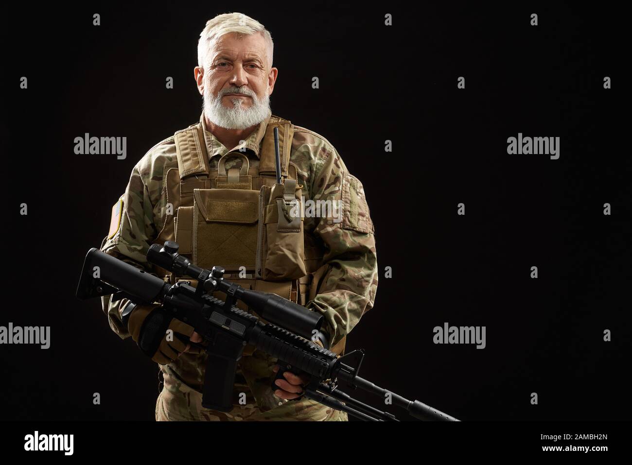 Front view of old military officer holding sniper rifle and looking at ...