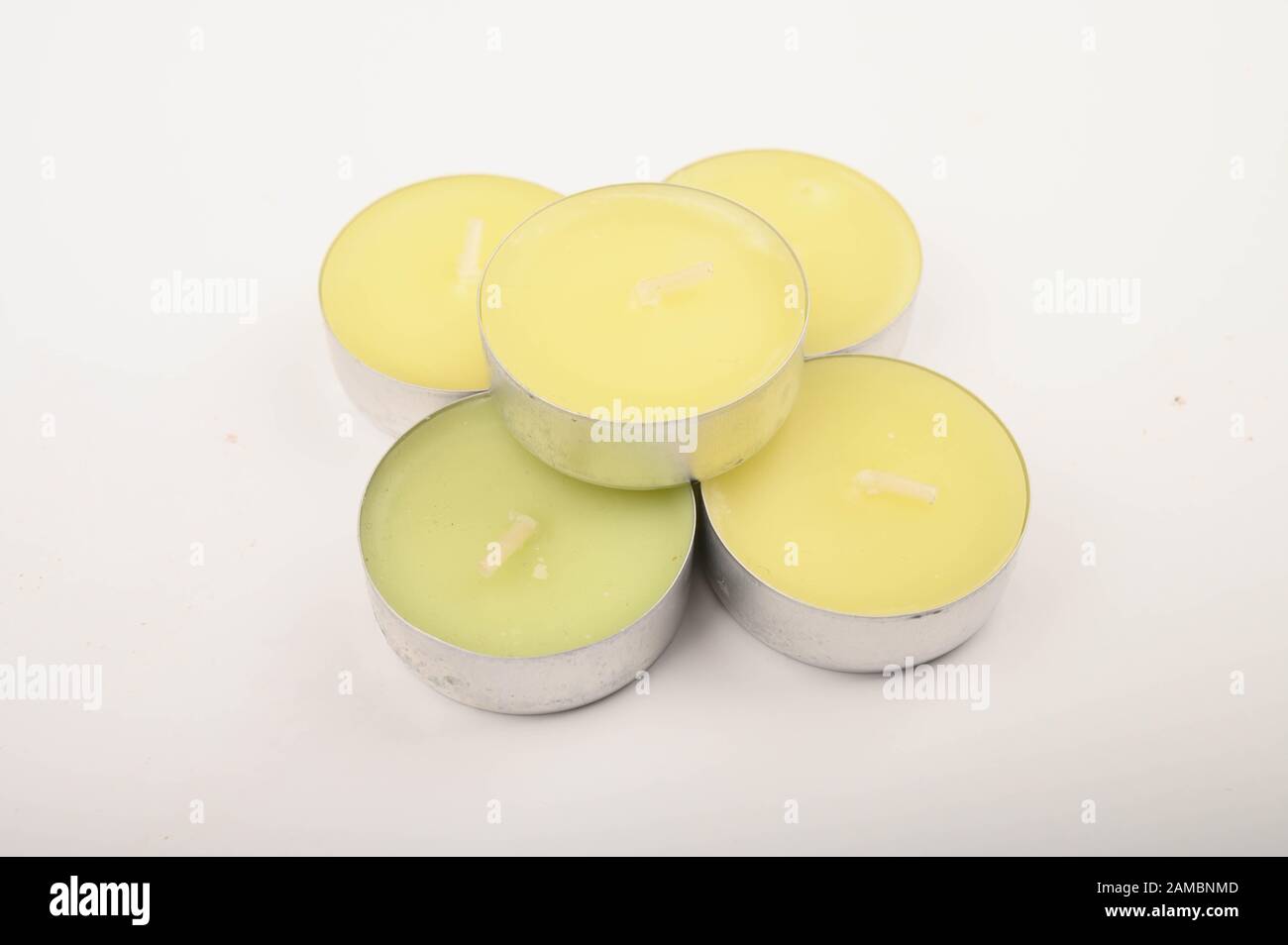 Five small colored candles in aluminum casings on a white background ...