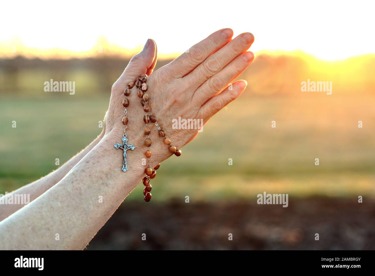 Woman praying outdoor with a crucifix at sunset Stock Photo - Alamy