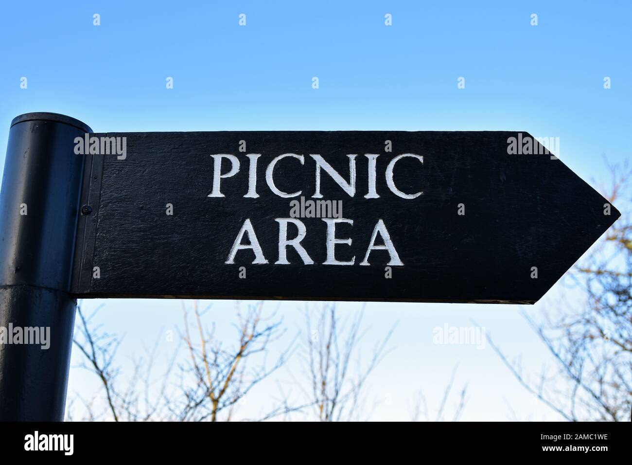 Picnic area signage on wooden post with arrow pointing right. Blue sky ...