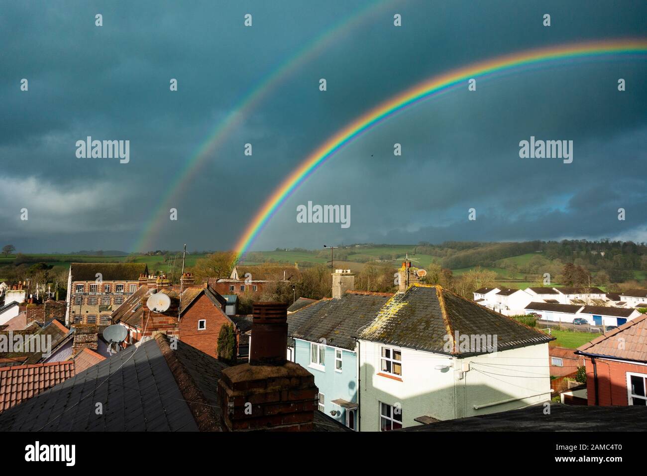 Double rainbow over houses against a grey stormy sky. Axminster, UK ...