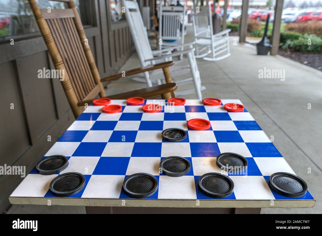 A blue and white checkers board with black and red game pieces, set up ...