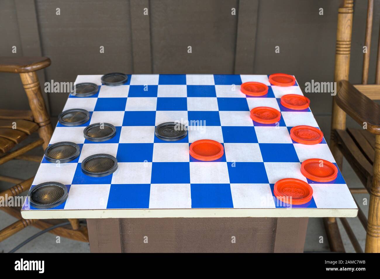 A blue and white checkers board with black and red game pieces, set up ...