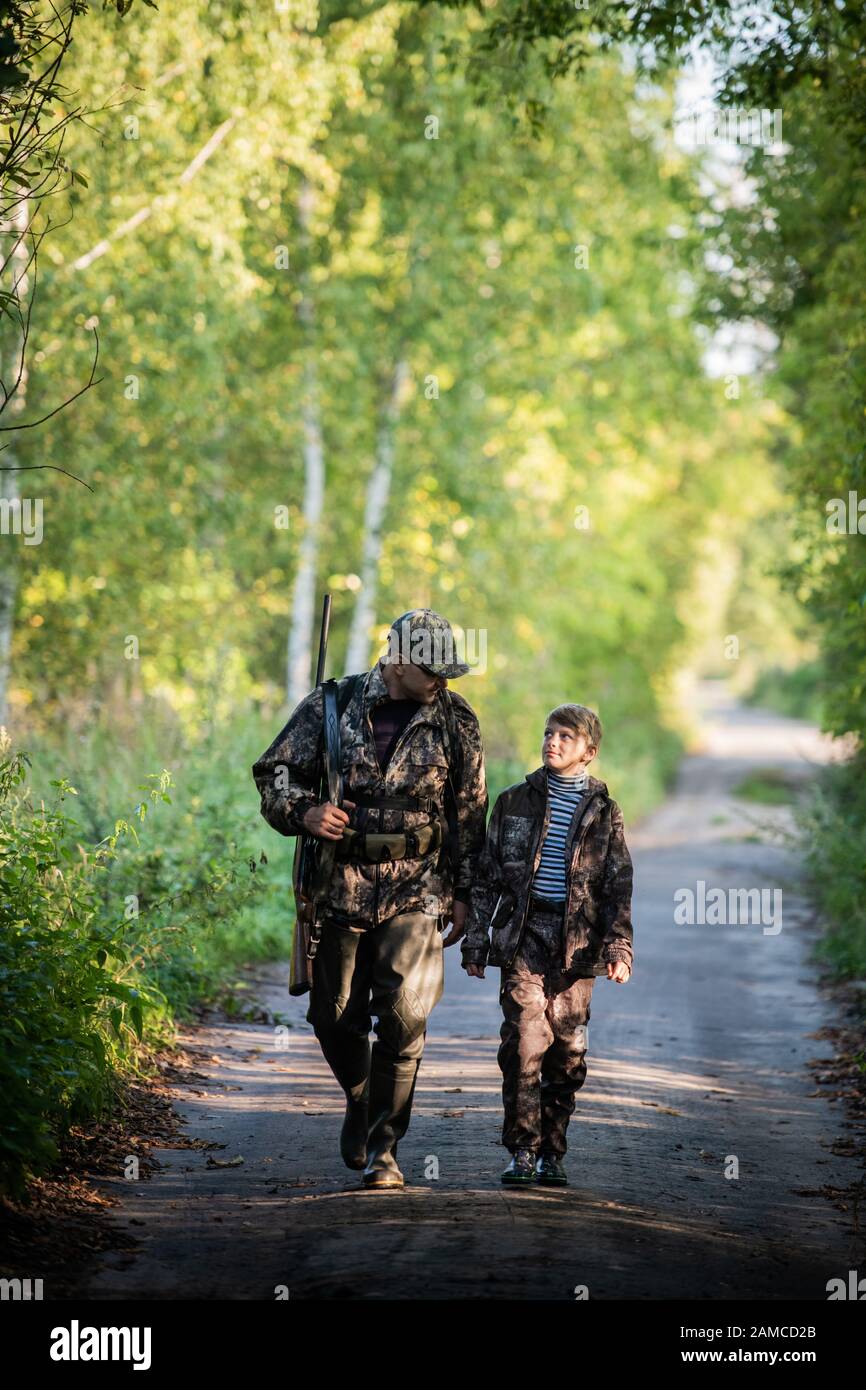 Father and son together hunting together. Walking the road in a forest ...
