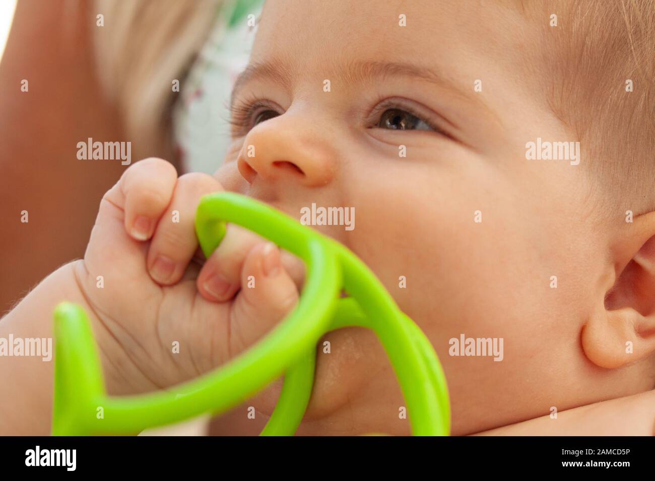 Nice closeup portrait of cute blond baby with brown eyes biting in a ...