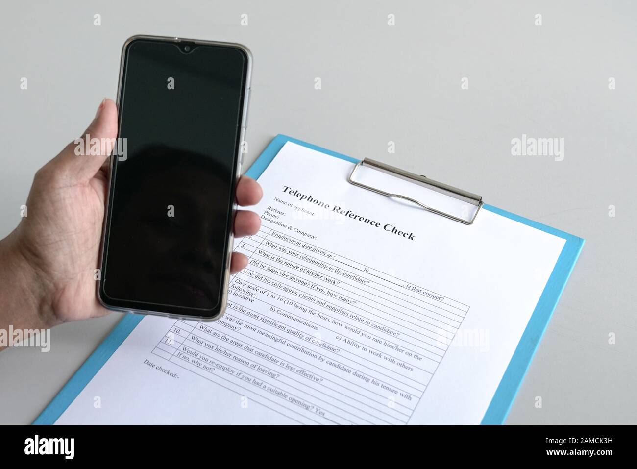 Making a call to conduct a telephone reference check on a potential ...