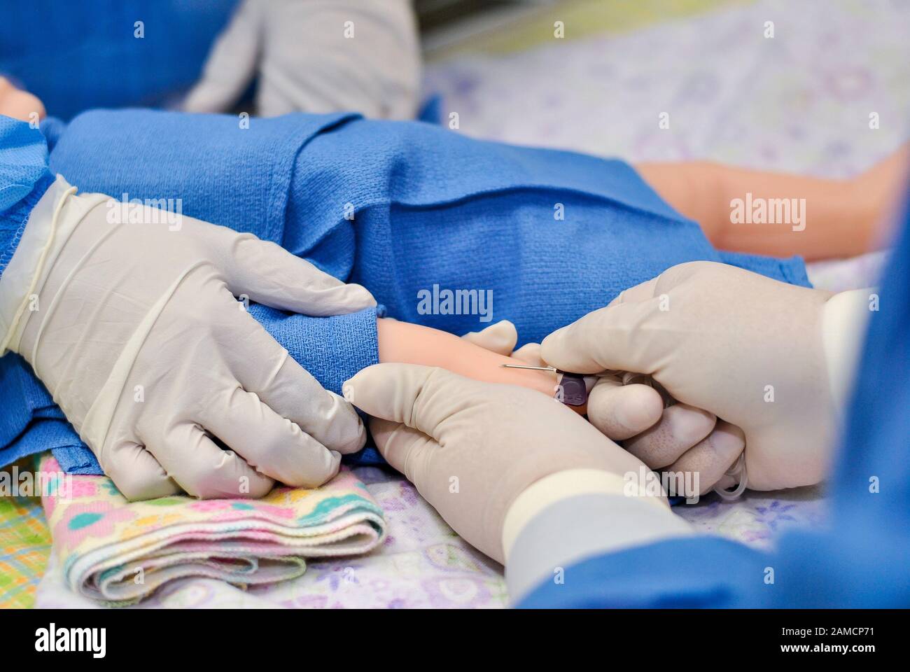 Doctors performing insertion of intravenous line on baby doll simulator ...