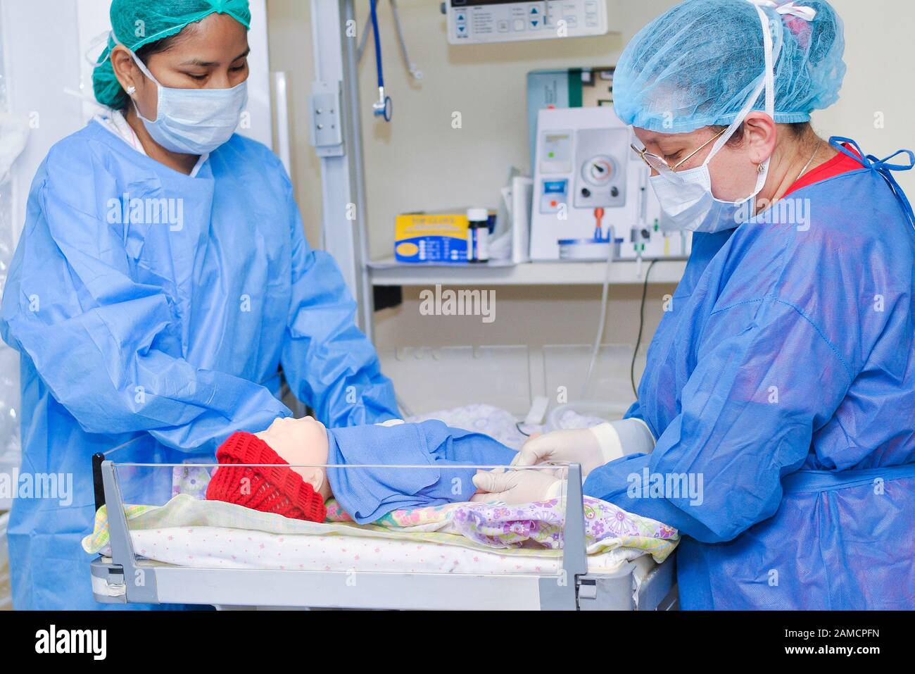 Doctors performing insertion of intravenous line on baby doll simulator ...
