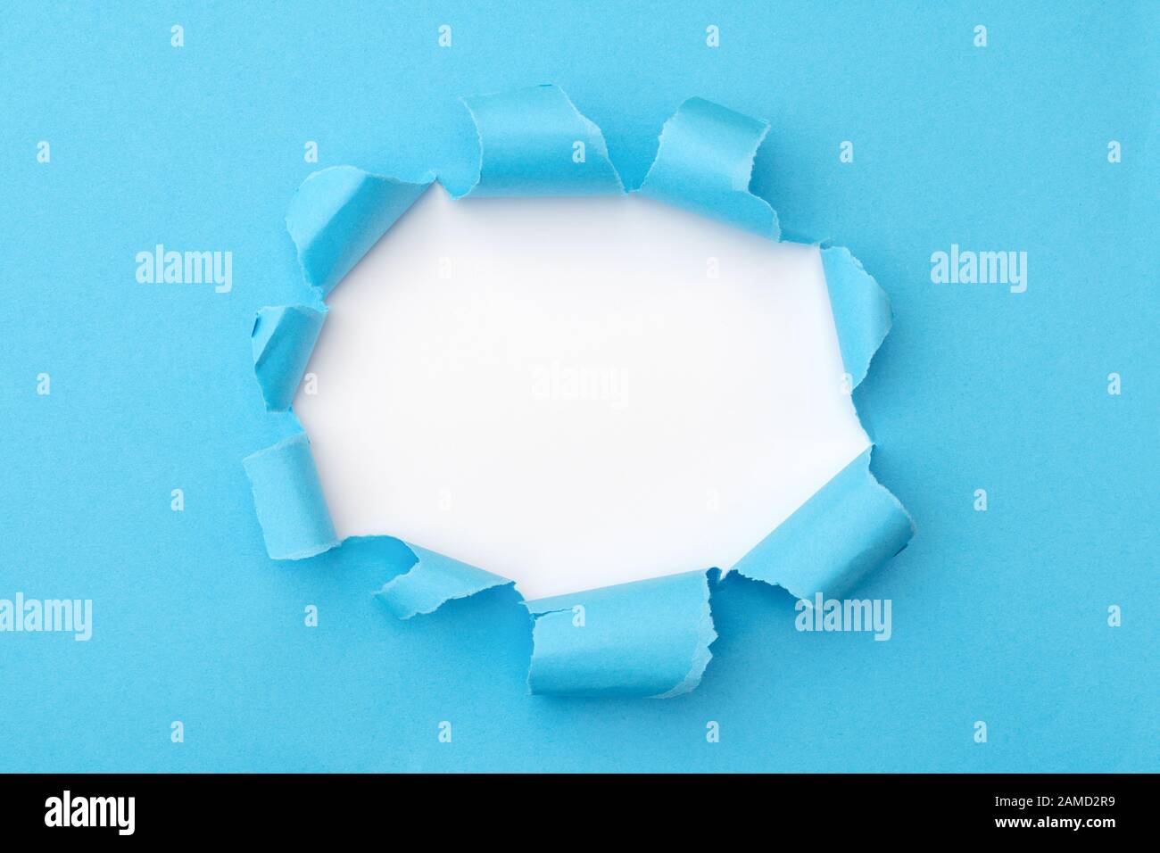 Blue paper with ripped hole in the middle background Stock Photo - Alamy