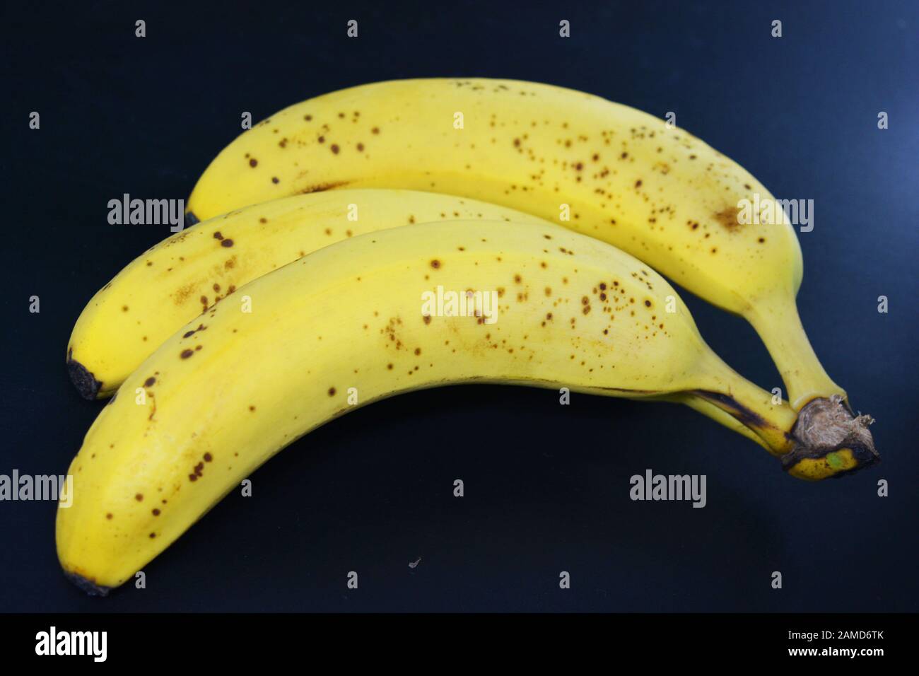 Sweet ripe yellow bananas, a bunch of three bananas with black pegmet ...