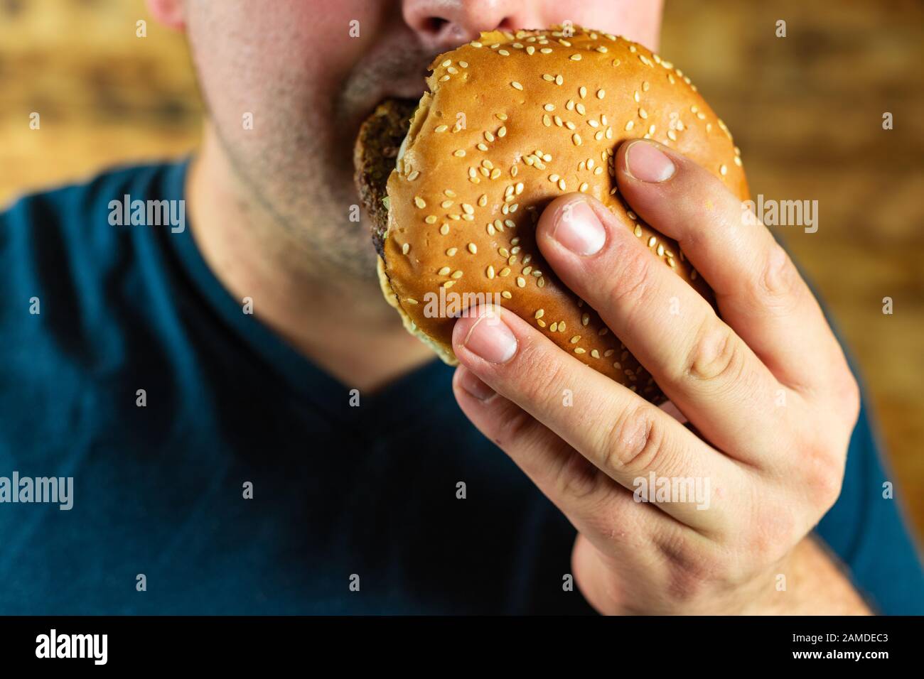 The hungry young man aggressively eats a burger. Fast food Stock Photo ...
