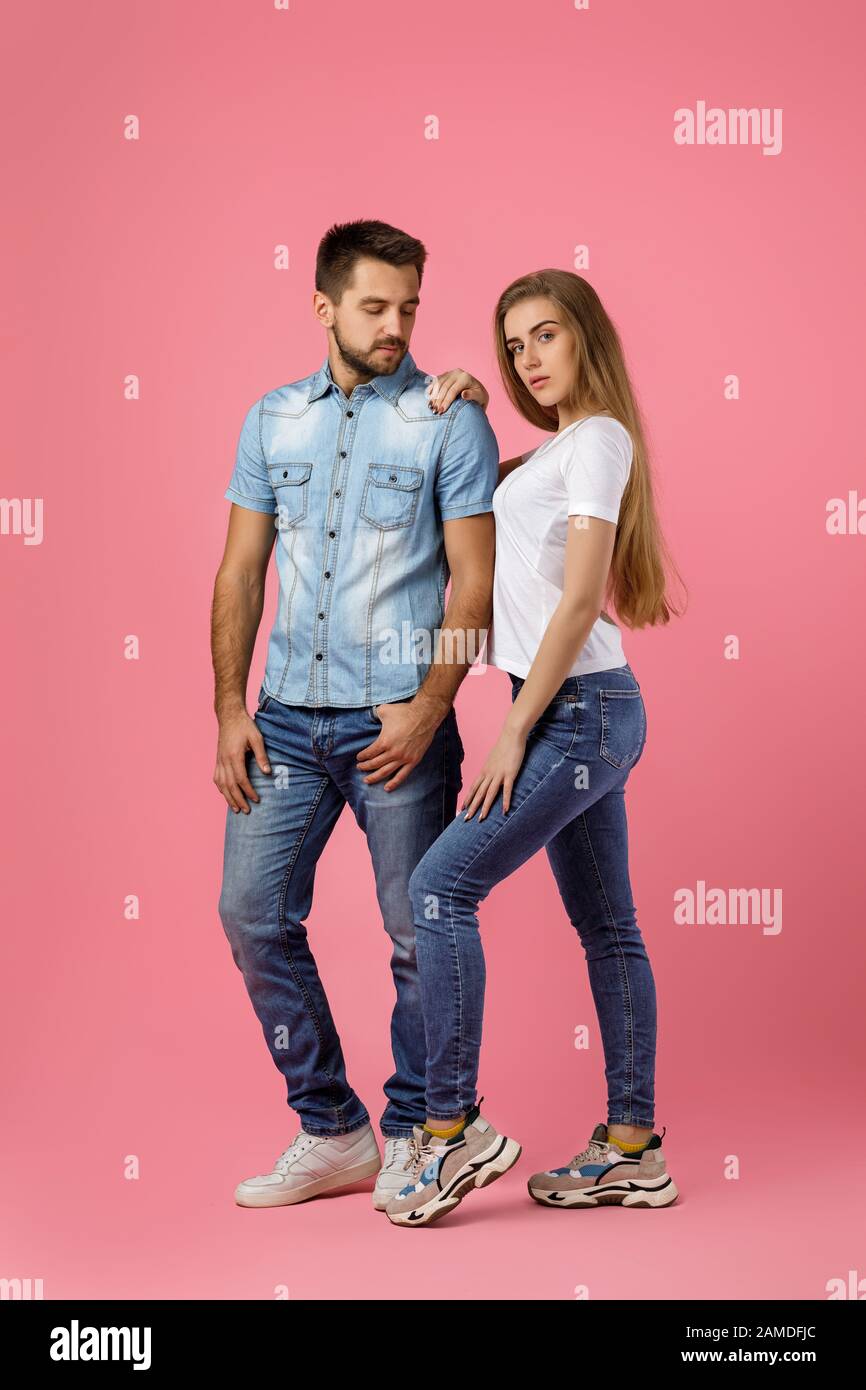 happy couple in love looking at camera and standing on pink background ...