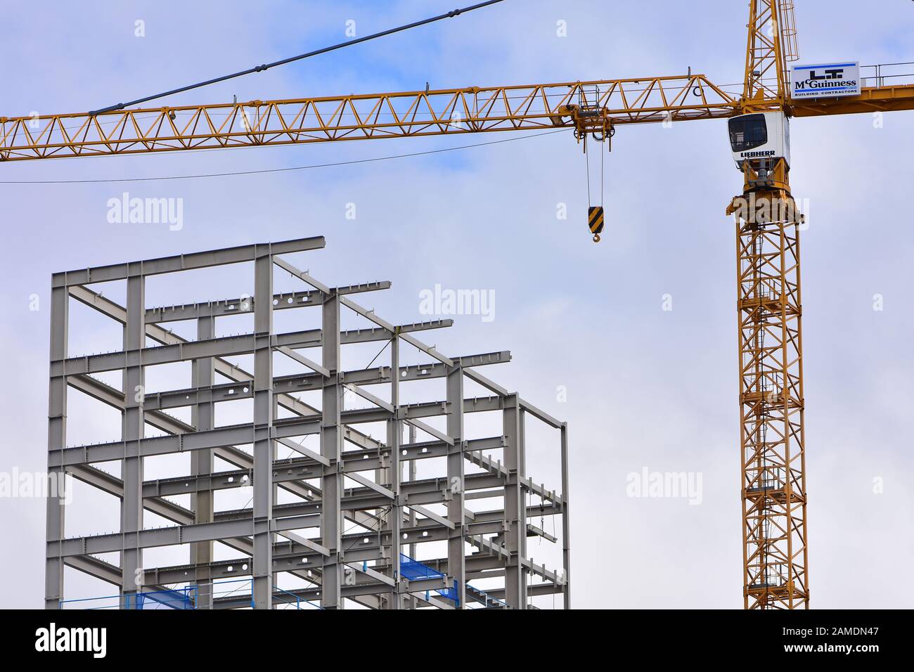 Yellow tower crane next to steel skeleton of building in construction ...