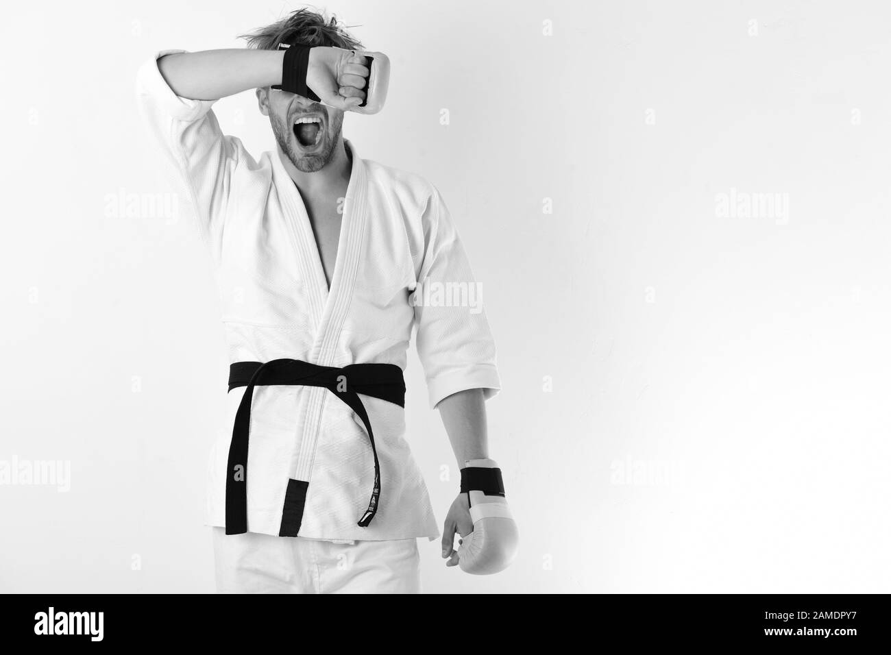 Guy poses in white kimono wearing golden boxing gloves. Man MMA fighter ...