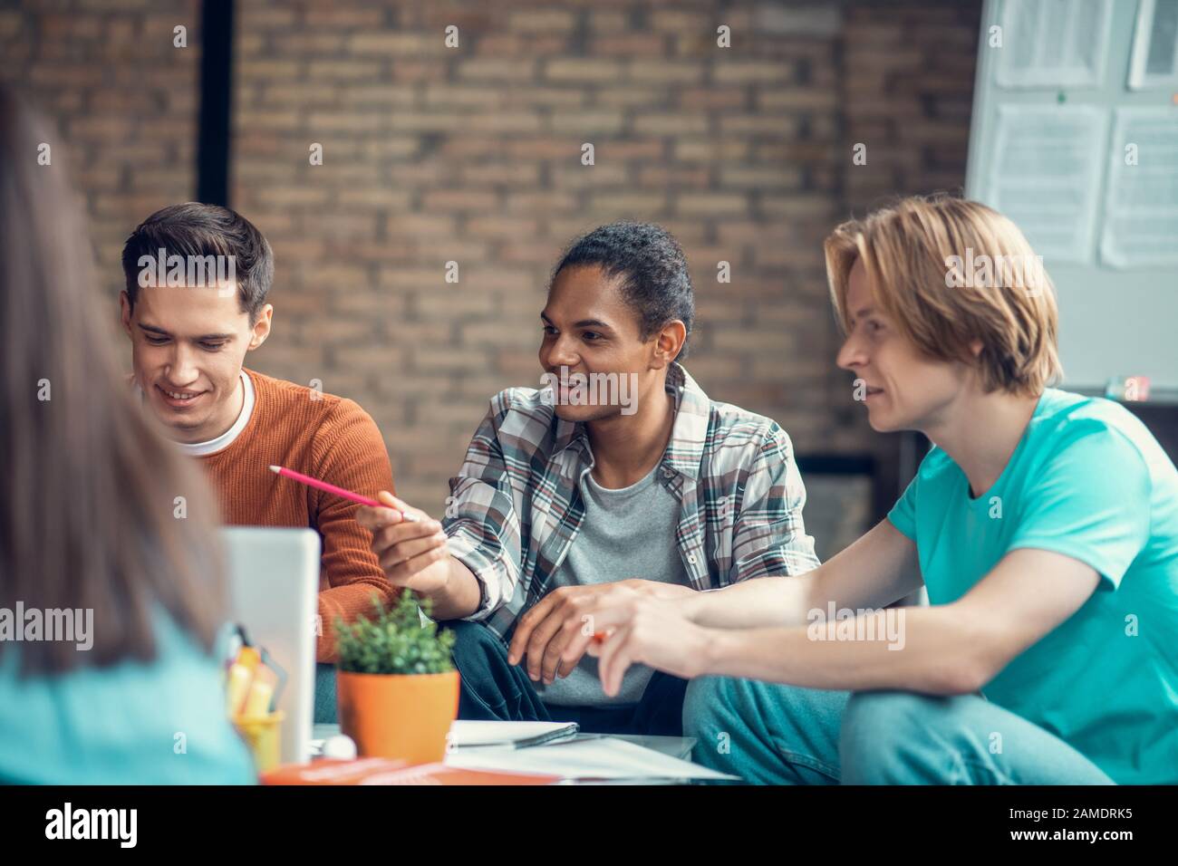 Handsome students sitting at the table while studying together Stock ...
