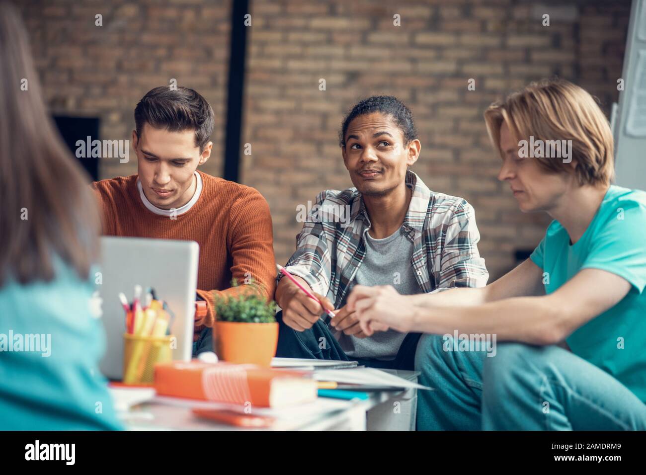 Dark-skinned student feeling thoughtful while studying with friends ...