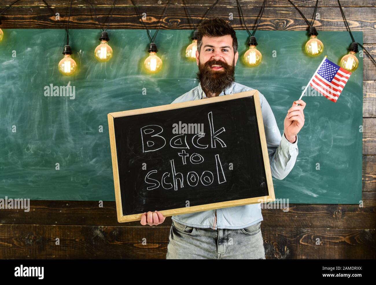 Man with beard on smiling face welcomes to american school, chalkboard ...