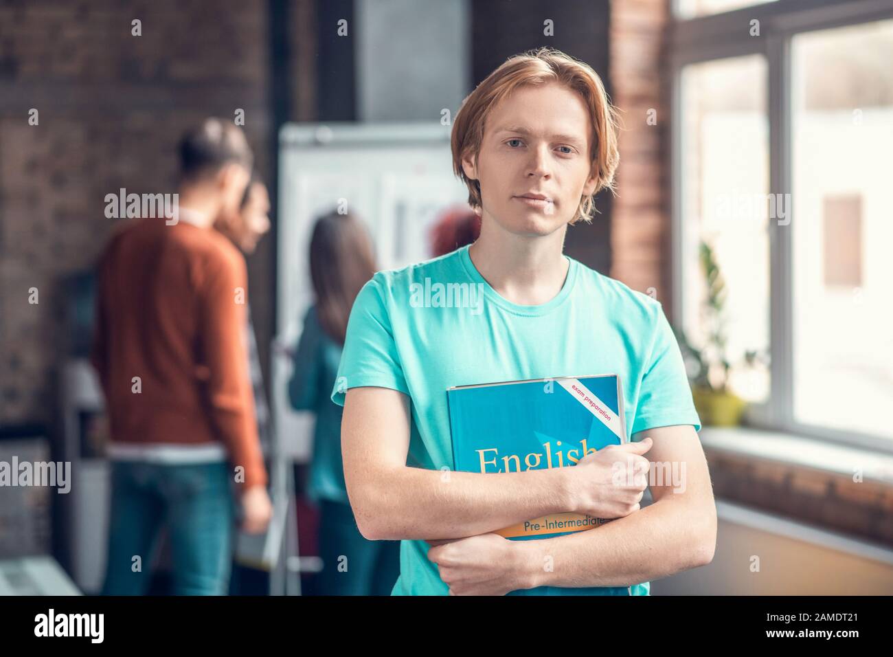 Handsome blue-eyed student holding English grammar book Stock Photo - Alamy