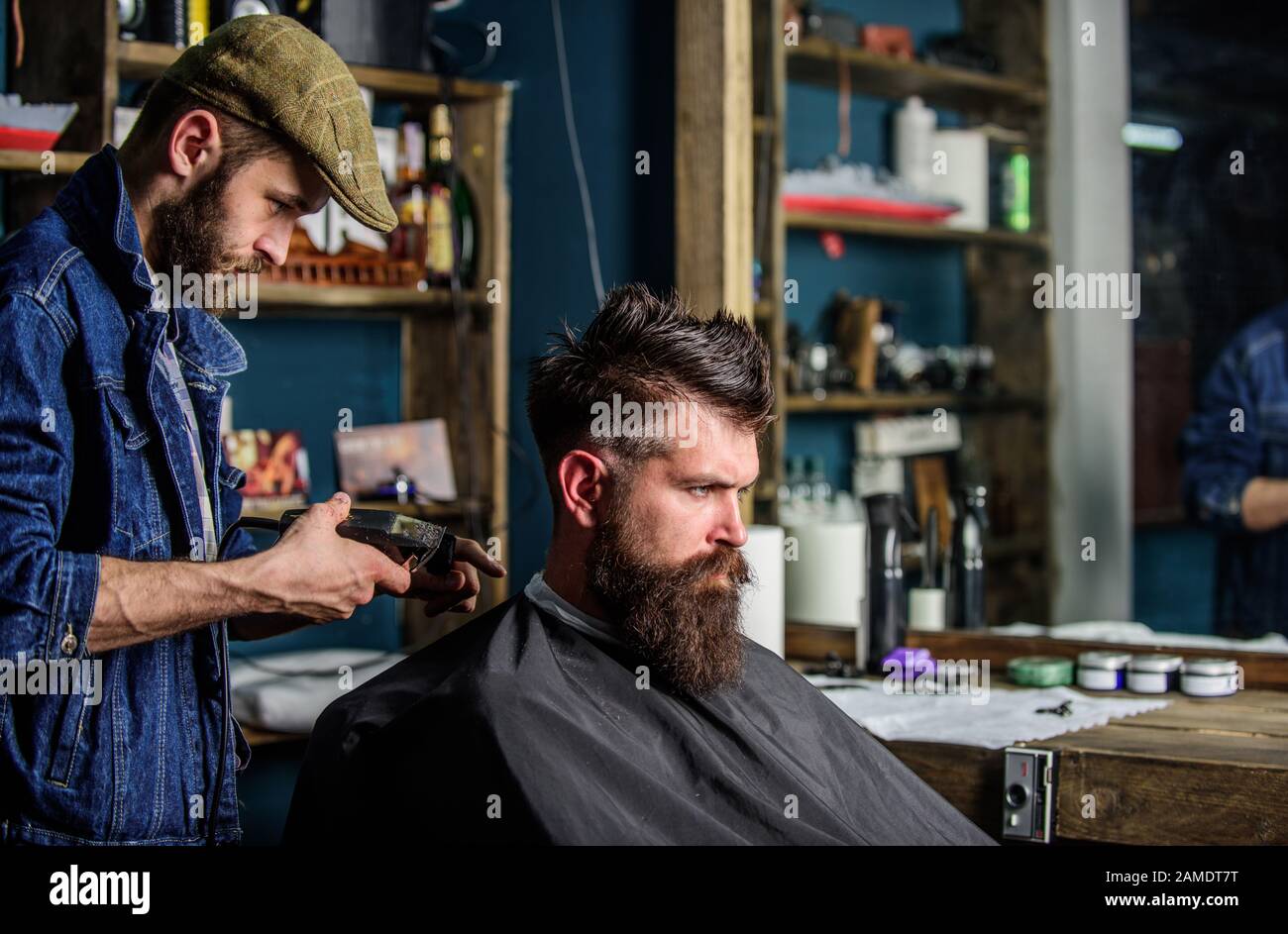 Barber with clipper trimming hair on nape of client. Hipster client ...