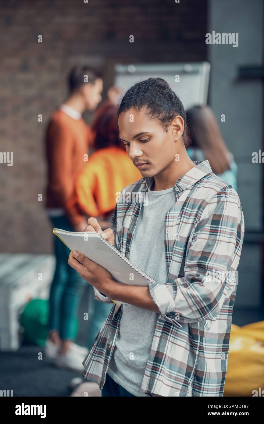 Student wearing checked shirt making notes while studying Stock Photo ...