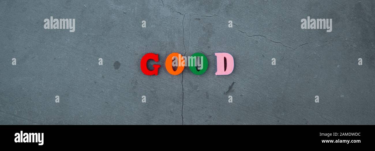 The multicolored good word is made of wooden letters on a grey ...