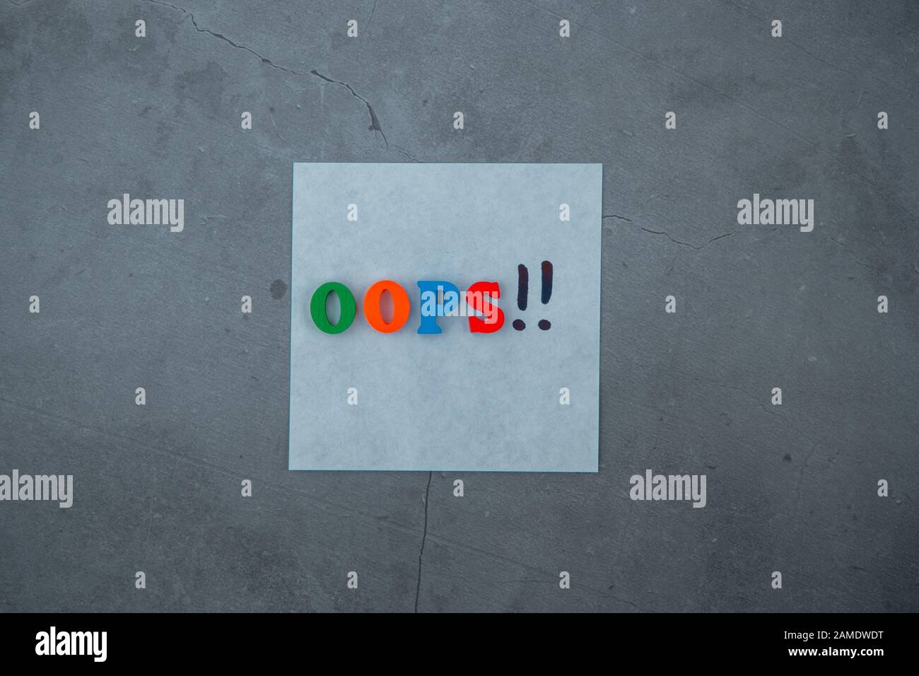 The multicolored oops word is made of wooden letters on a grey ...