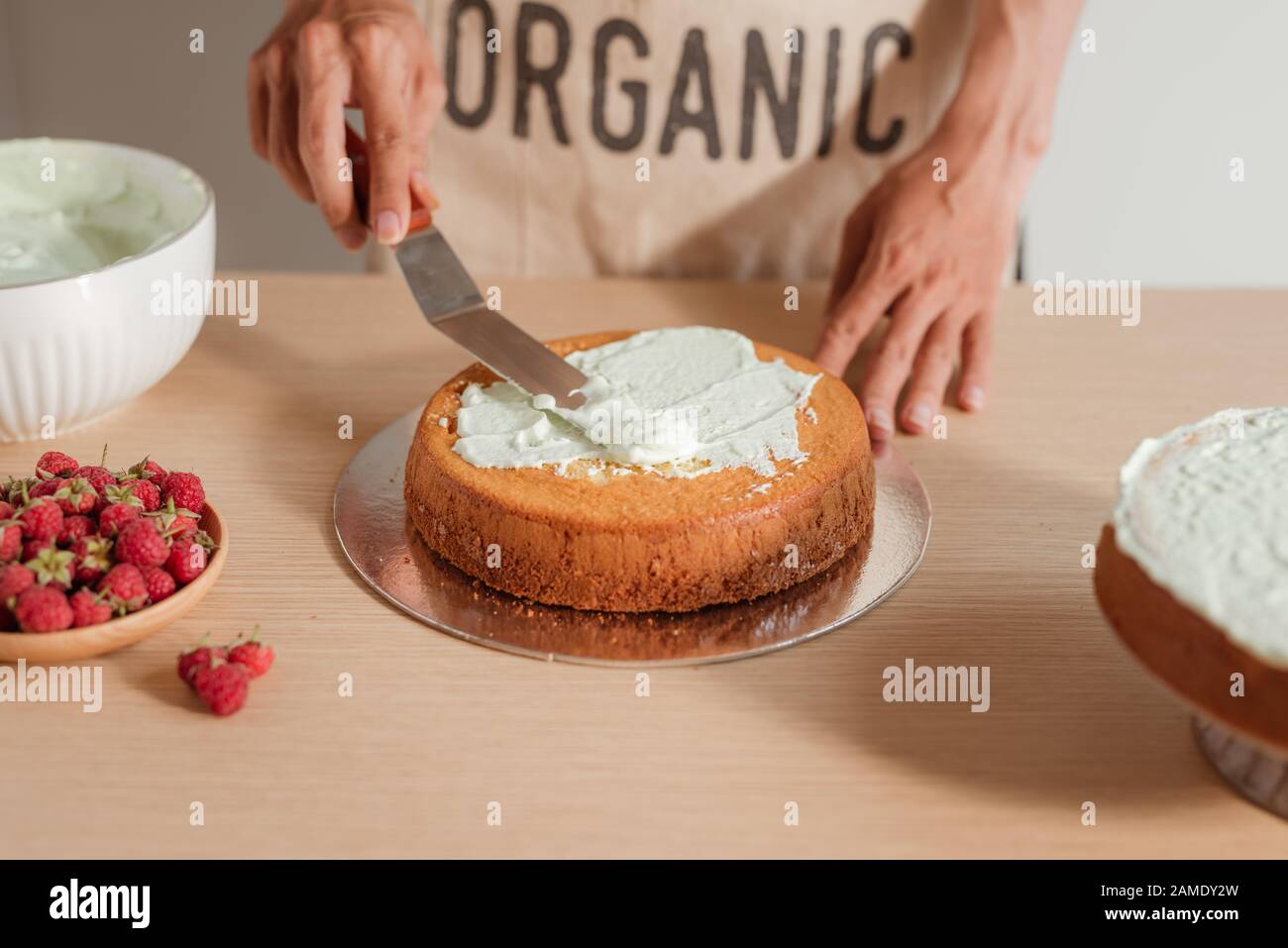 Man pastry chef put icing cream on sponge cake. Making sponge cake ...