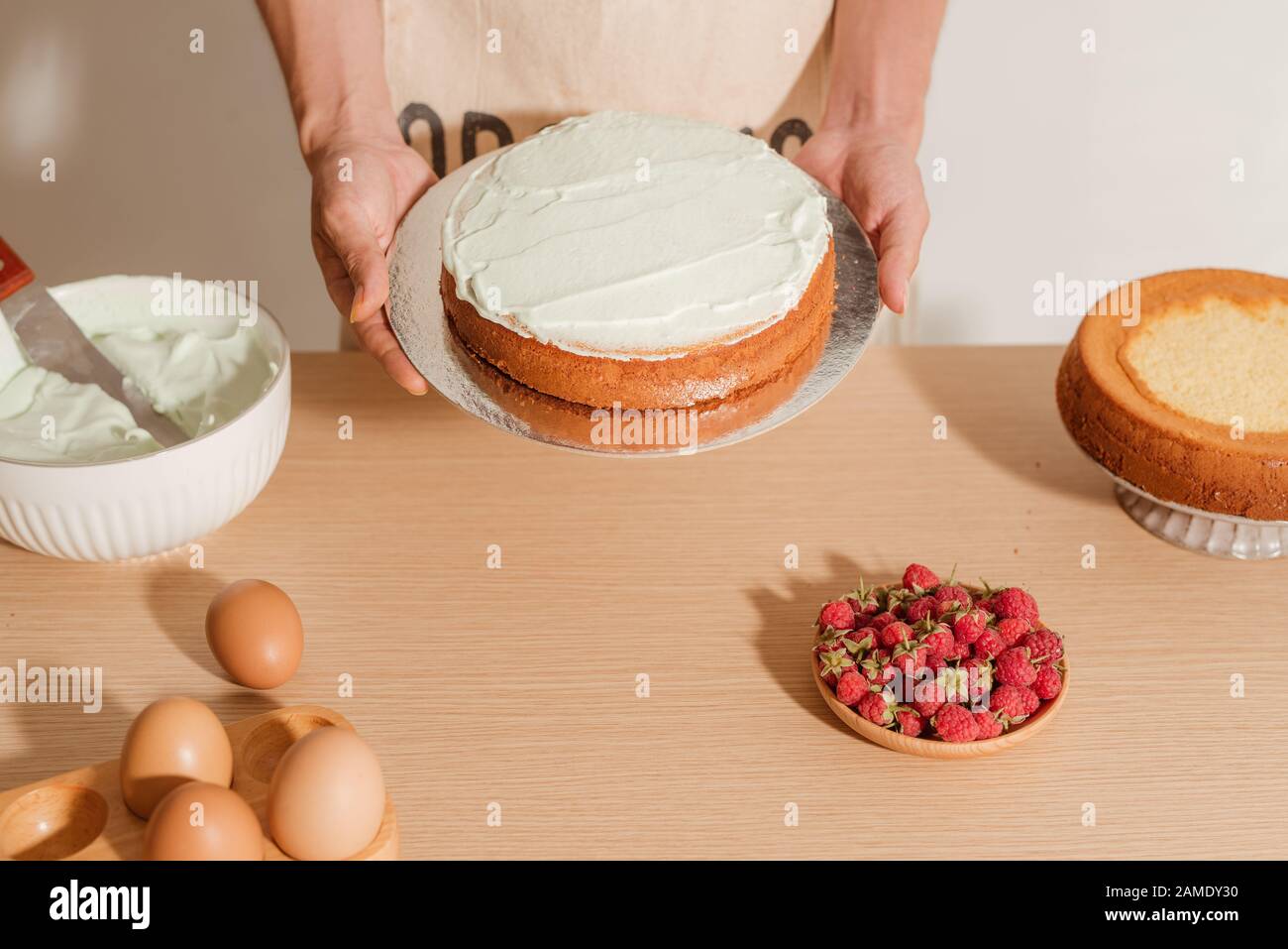 Male pastry chef is holding sponge cake with many various ingredients ...