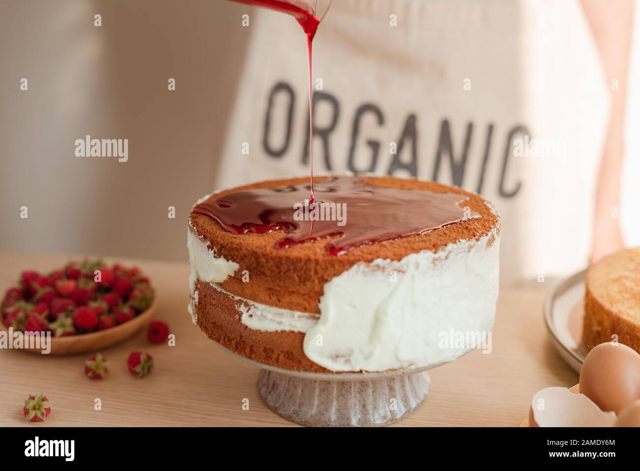 fresh sponge cake with raspberry syrup being poured over the top ...