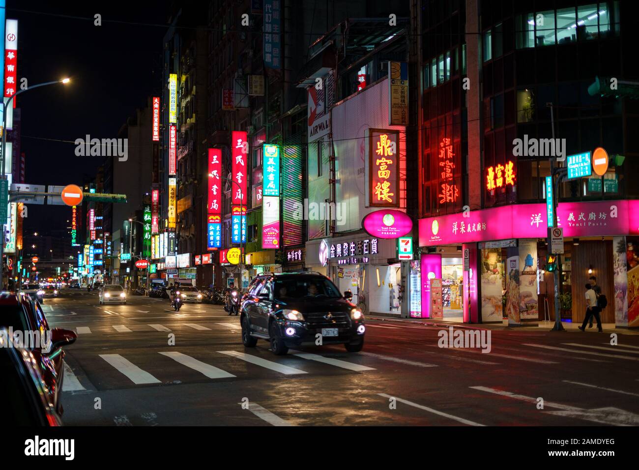 Busy urban street at night lit by colorful advertising neon signs with ...