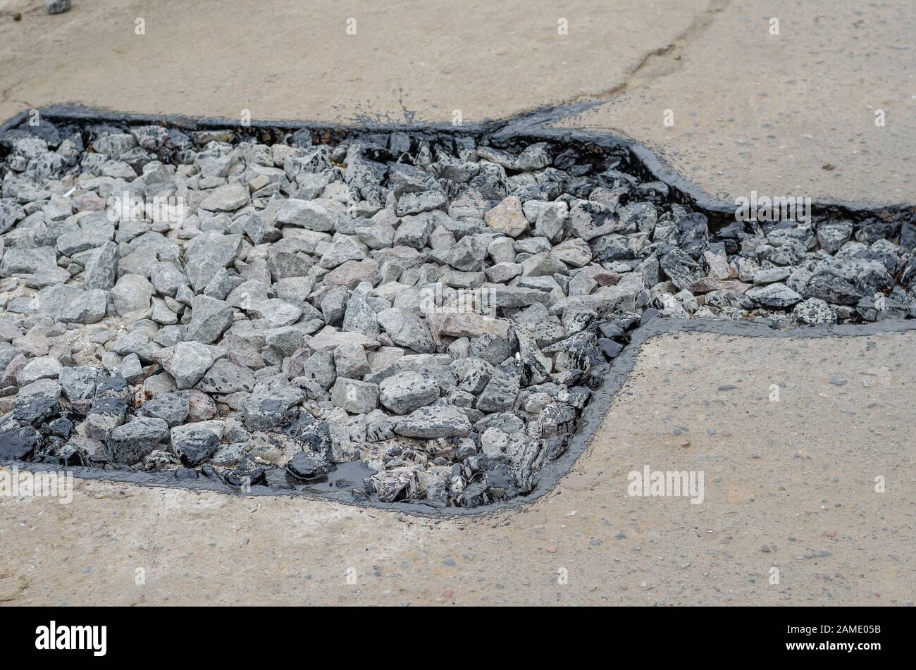 Hole in the asphalt road. The edges of the pit are treated with resin ...