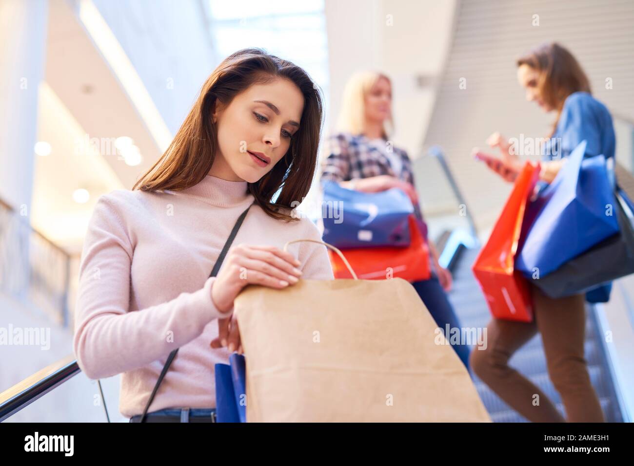Young woman opening shopping bag in shopping mall Stock Photo - Alamy
