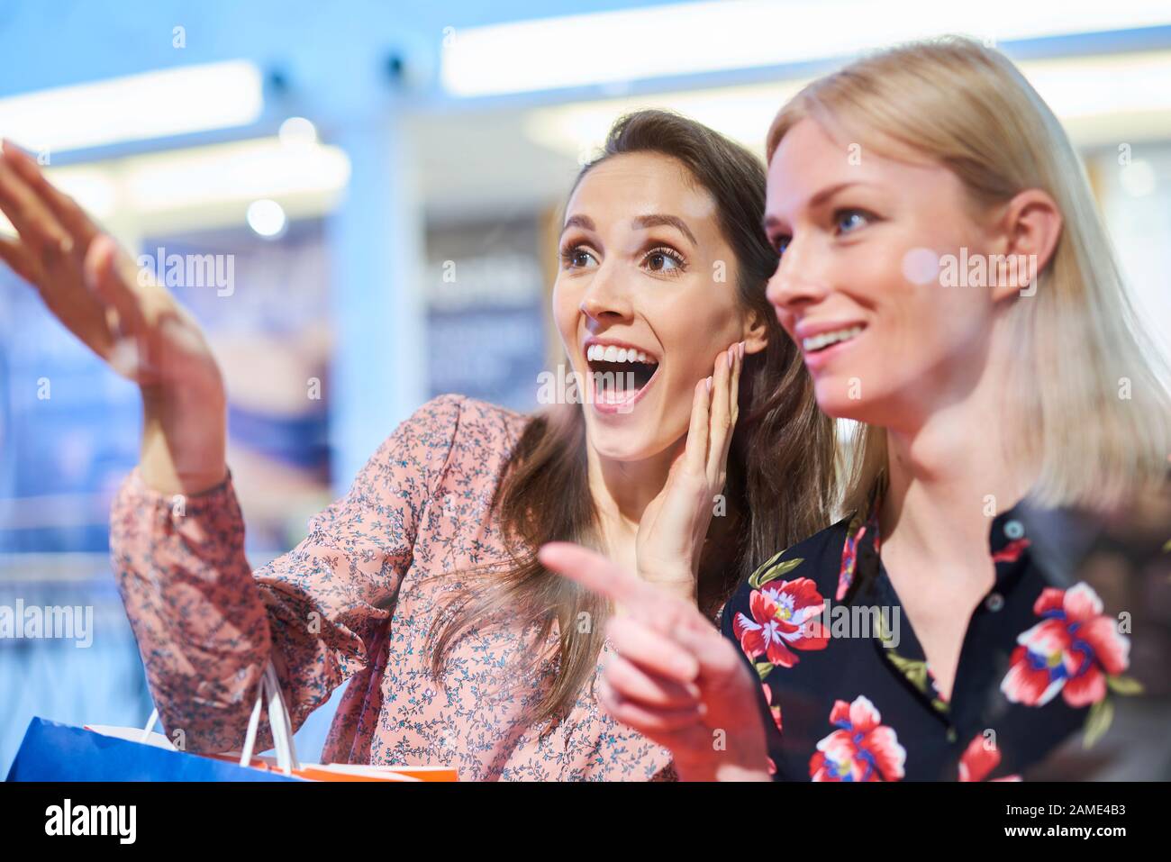 Two happy women looking at window display Stock Photo - Alamy