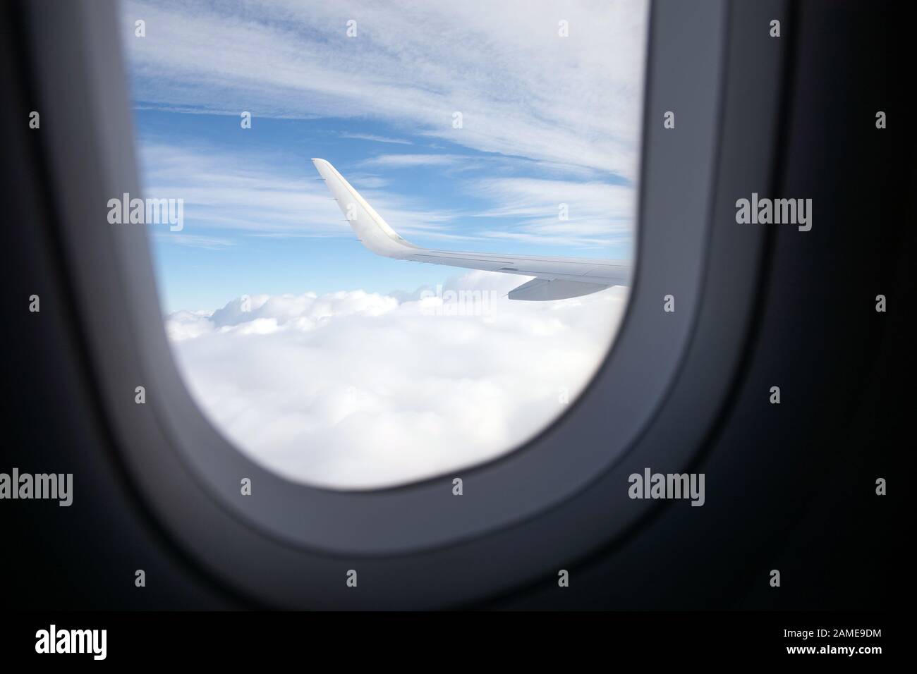 Wing of airplane above clouds viewed from its cabin Stock Photo - Alamy