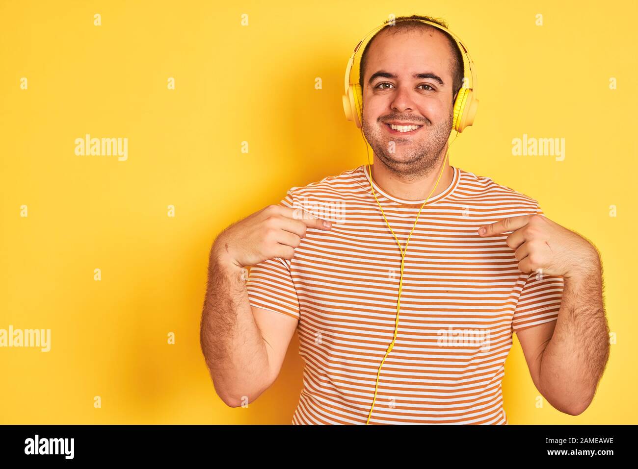 Young man listening to music using headphones standing over isolated ...