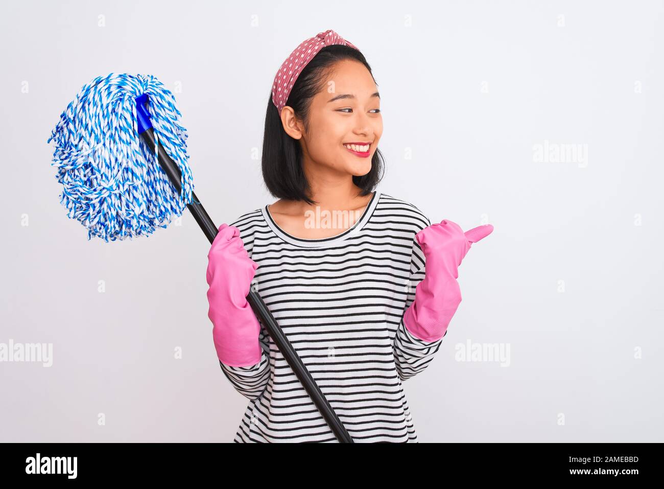 Young chinese cleaner woman wearing gloves holding mop over isolated ...
