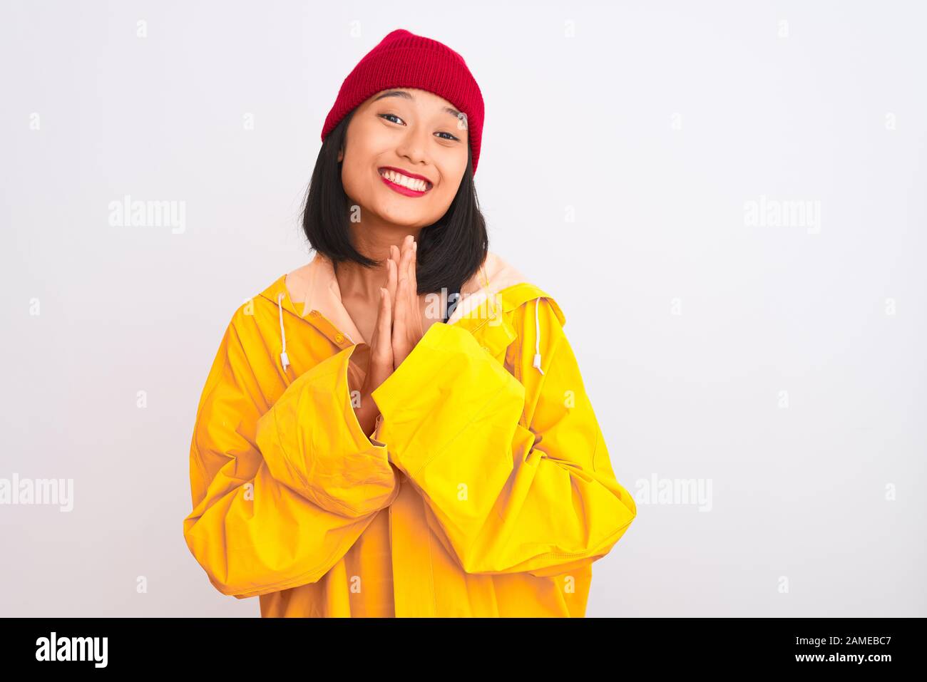 Young beautiful chinese woman wearing raincoat and wool cap over ...