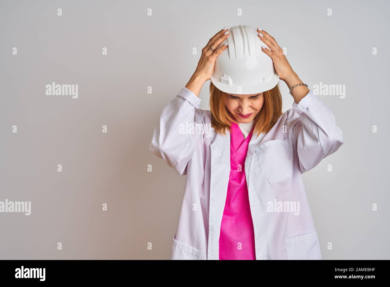 Redhead caucasian woman engineer wearing safety helmet over isolated ...