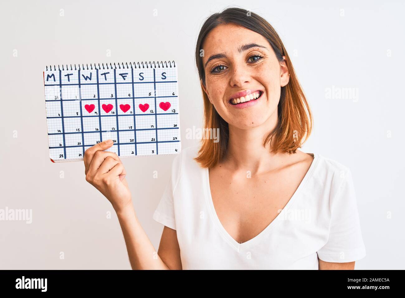 Beautiful redhead woman holding menstruation calendar over isolated ...