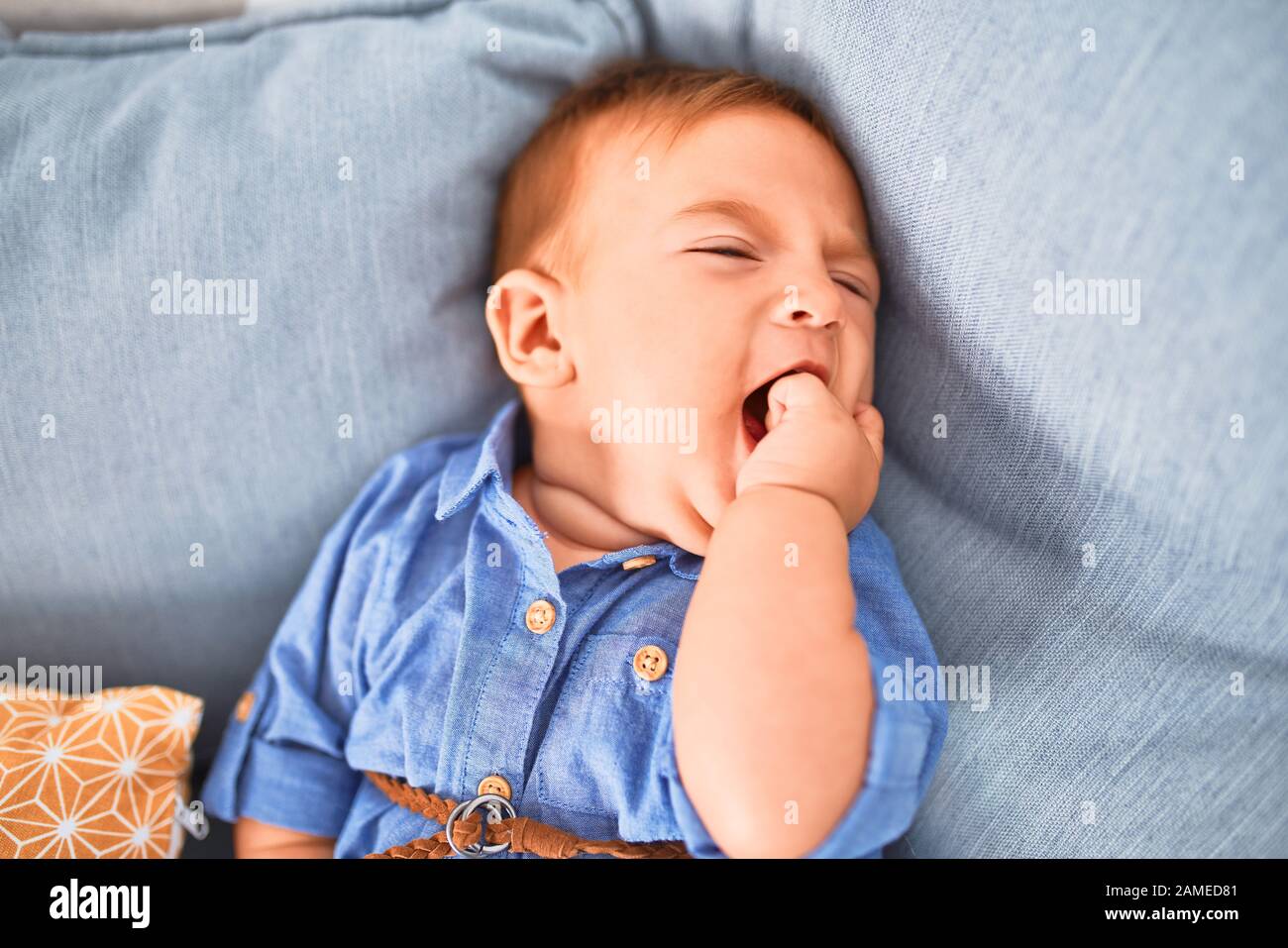 Adorable baby lying down on the sofa at home. Newborn crying and ...