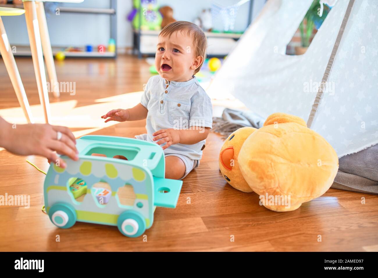 Adorable toddler siting on the floor crying around lots of toys at ...
