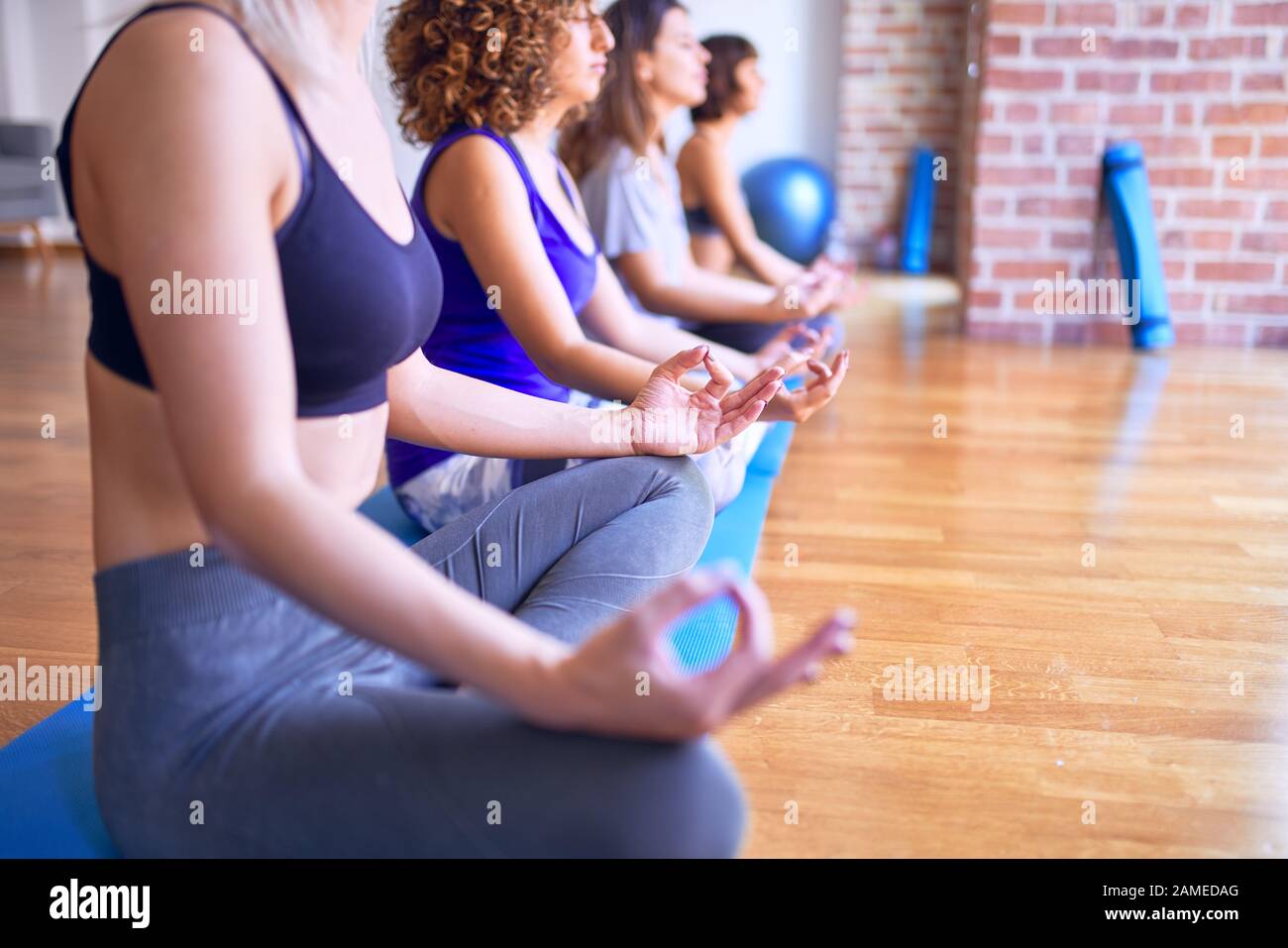 Young beautiful group of sportswomen smiling happy practicing yoga ...