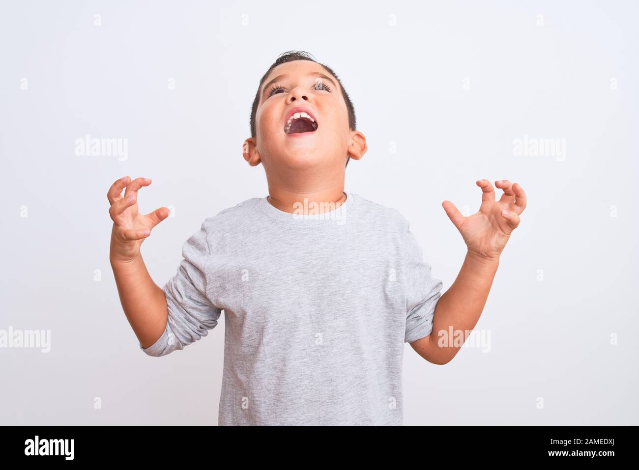 Beautiful kid boy wearing grey casual t-shirt standing over isolated ...
