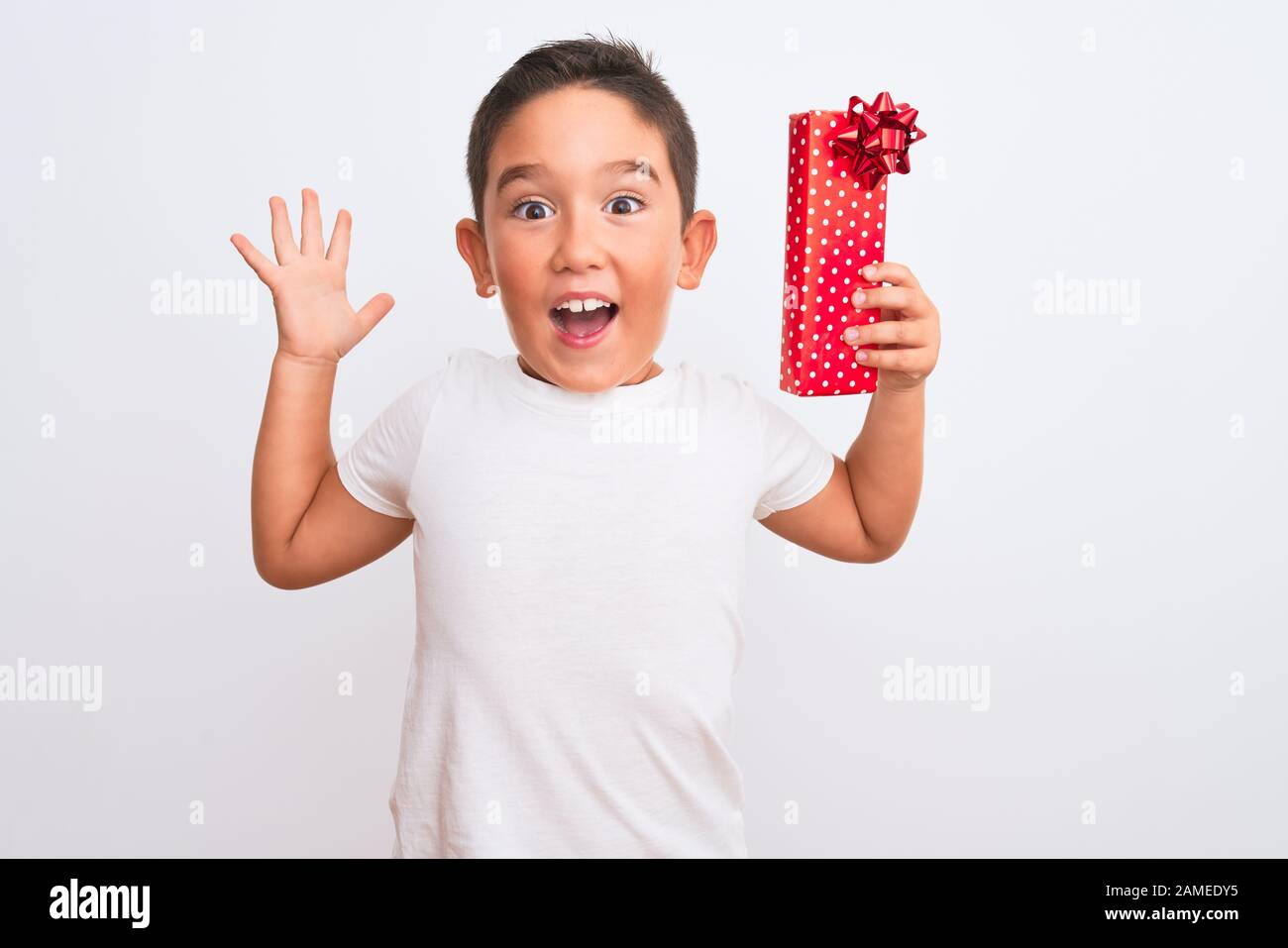 Beautiful kid boy holding birthday gift standing over isolated white ...