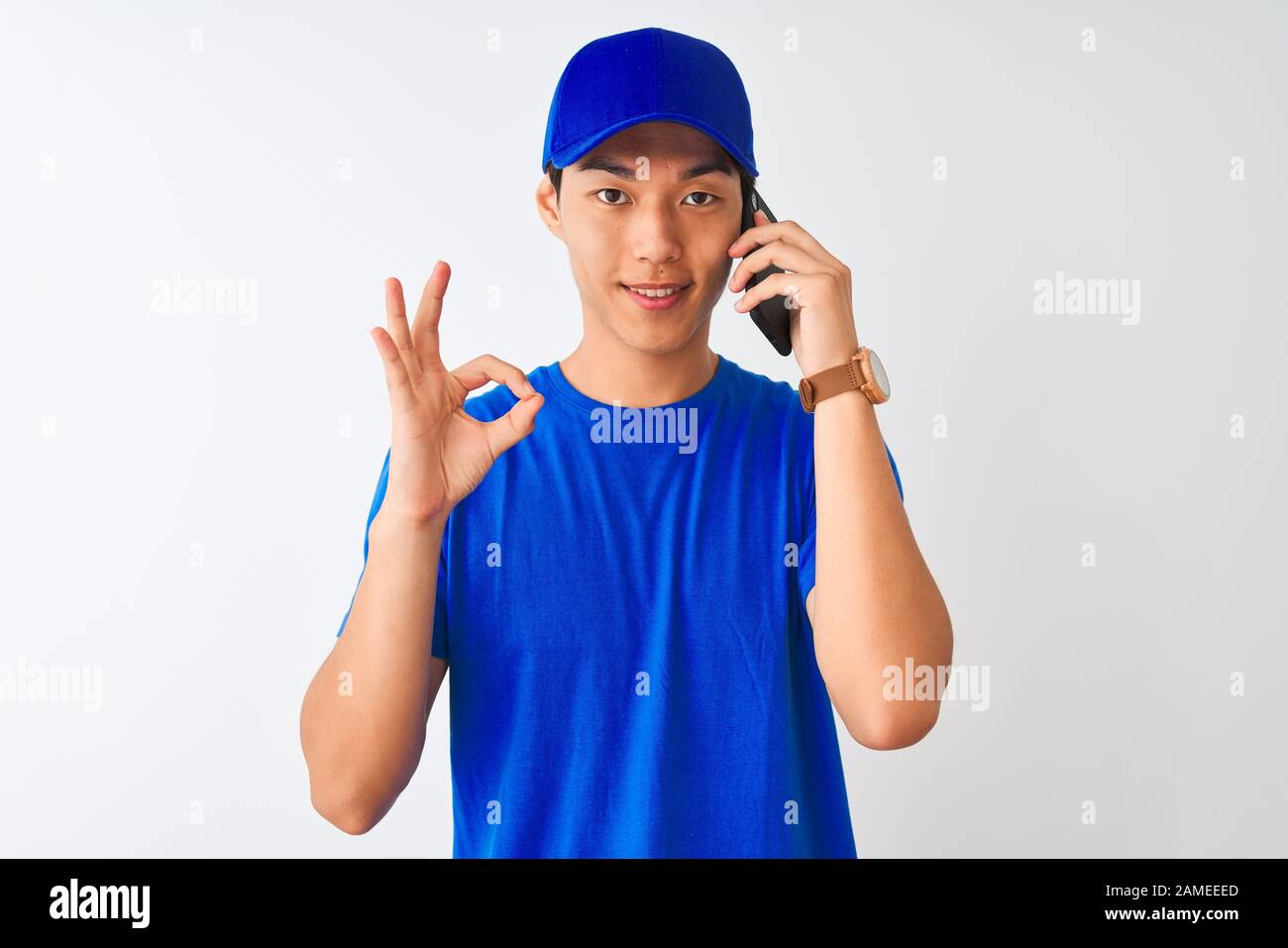Chinese deliveryman wearing cap talking on the smartphone over isolated ...