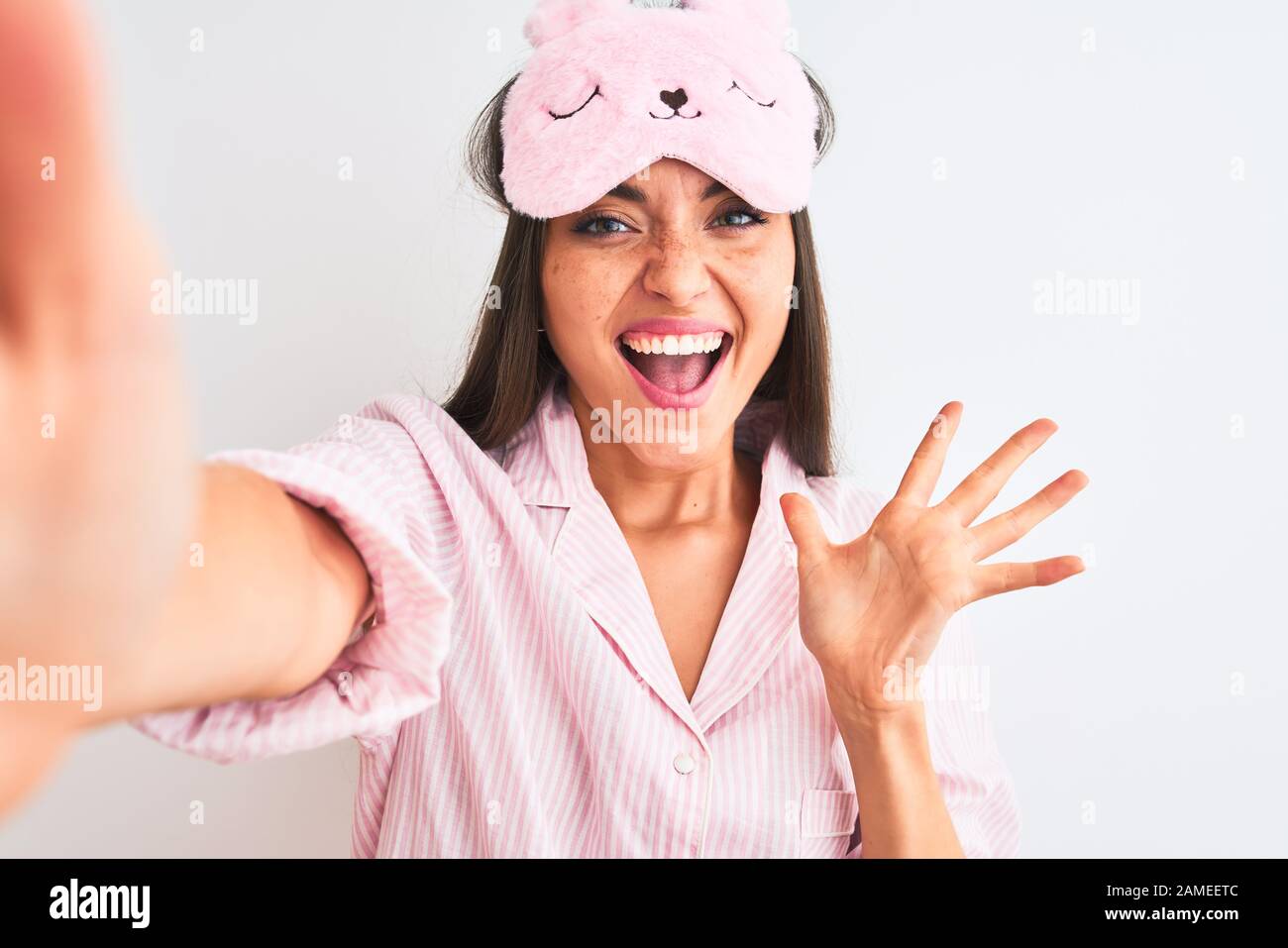 Young woman wearing sleep mask make selfie by camera over isolated ...