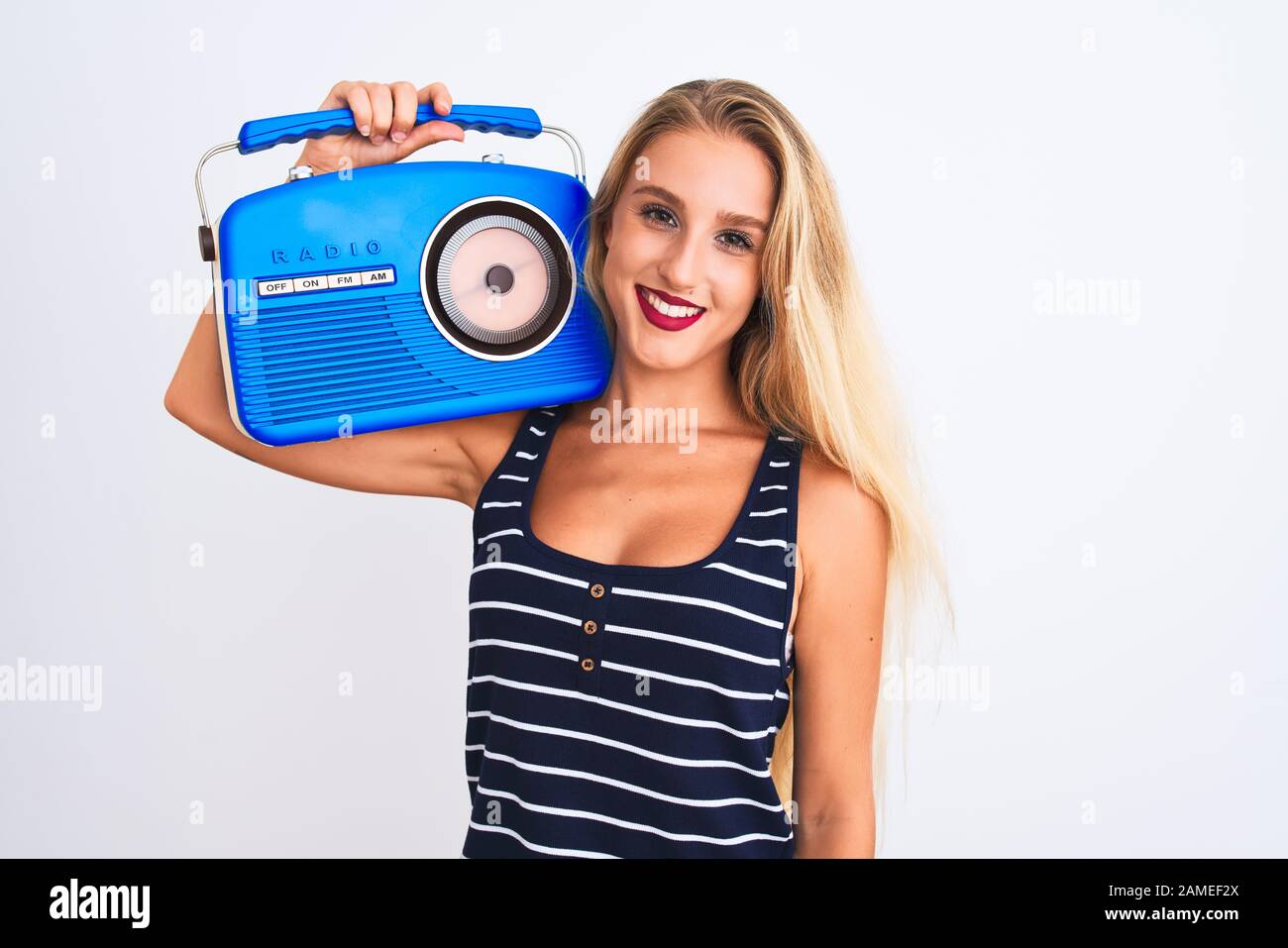 Young beautiful woman holding vintage radio standing over isolated ...