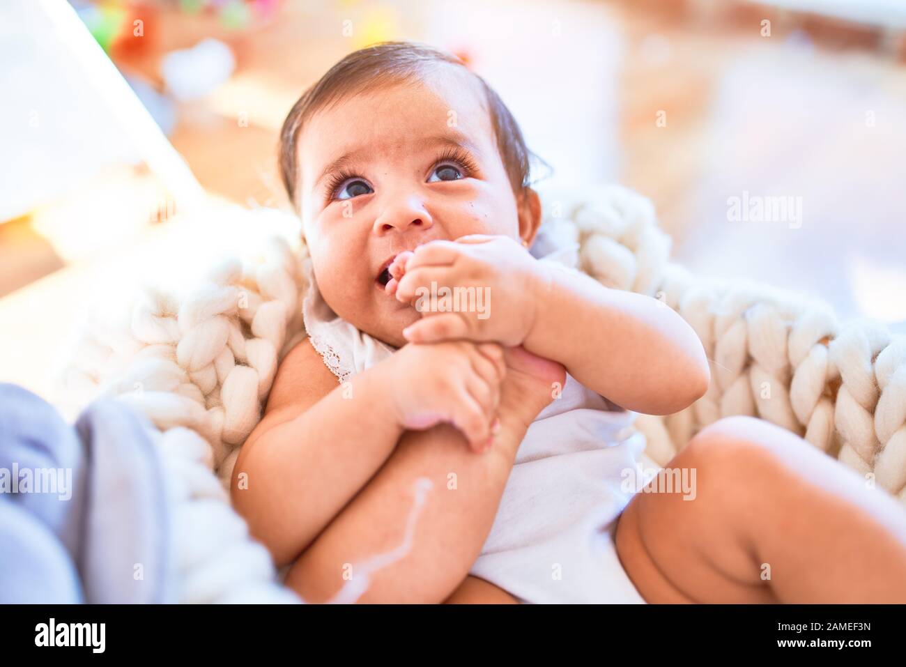 Beautiful infant happy at kindergarten around colorful toys lying ...